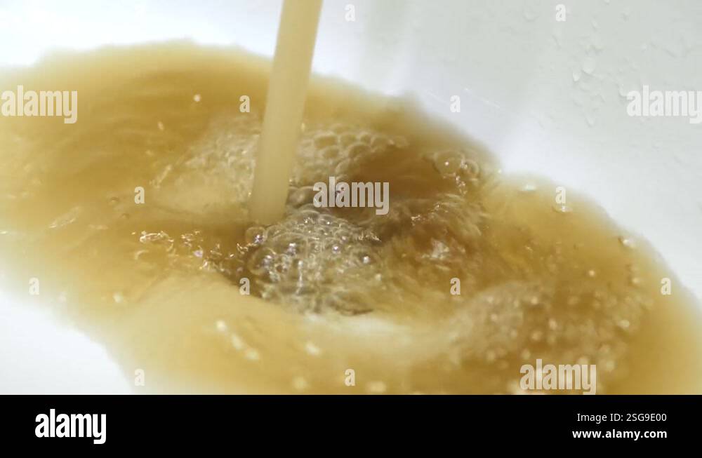 Woman's hand open the tap, rusty water running into a white sink ...