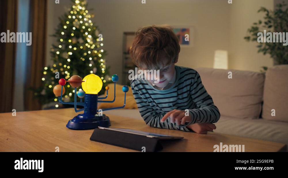 Focused boy with brown hair explores the planets. In front of him is ...