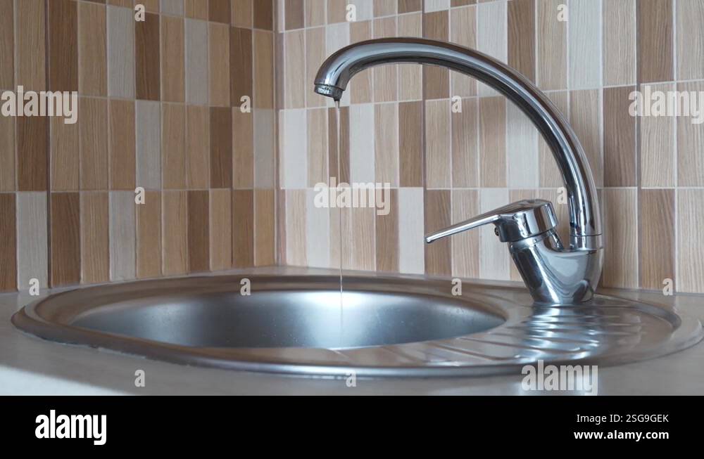 Water flows in a thin stream from tap in kitchen, from tap is flows ...