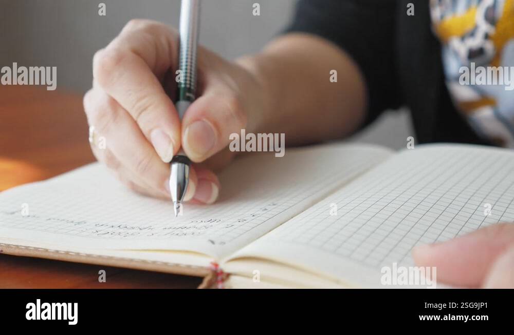 A woman writes with a pen in a notebook, close-up. The girl makes a to ...