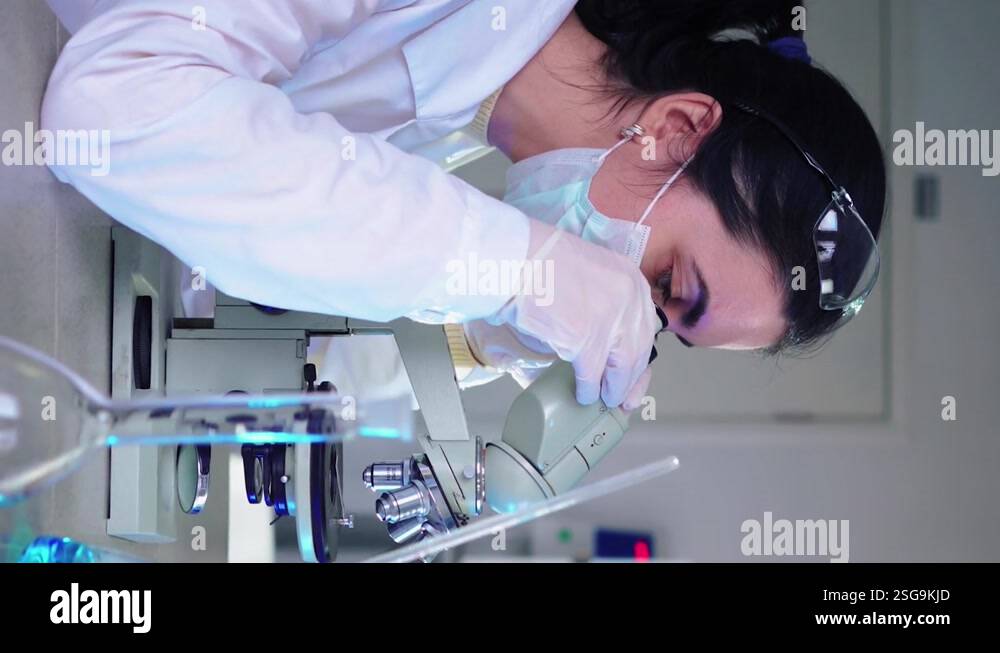 Female Microbiologist Looking into Microscope in Medical Science ...