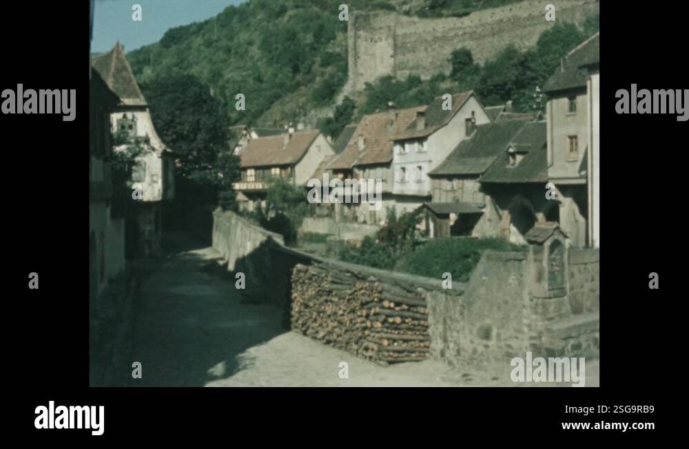 1950s: Houses in village, castle on hillside. Clapboard. Water flowing ...