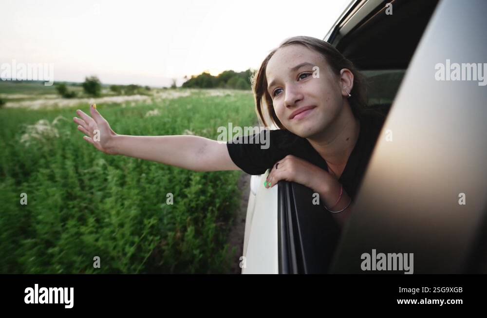 Happy family travel. Little girl leaning out of car window waving hand ...