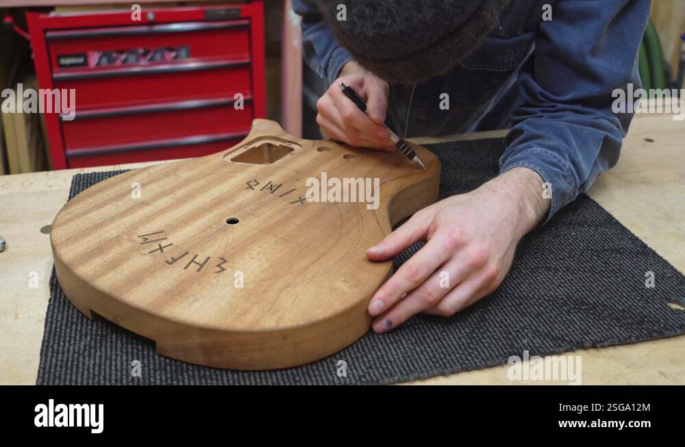 Professional luthier drawing curve for carving on the back of guitar ...