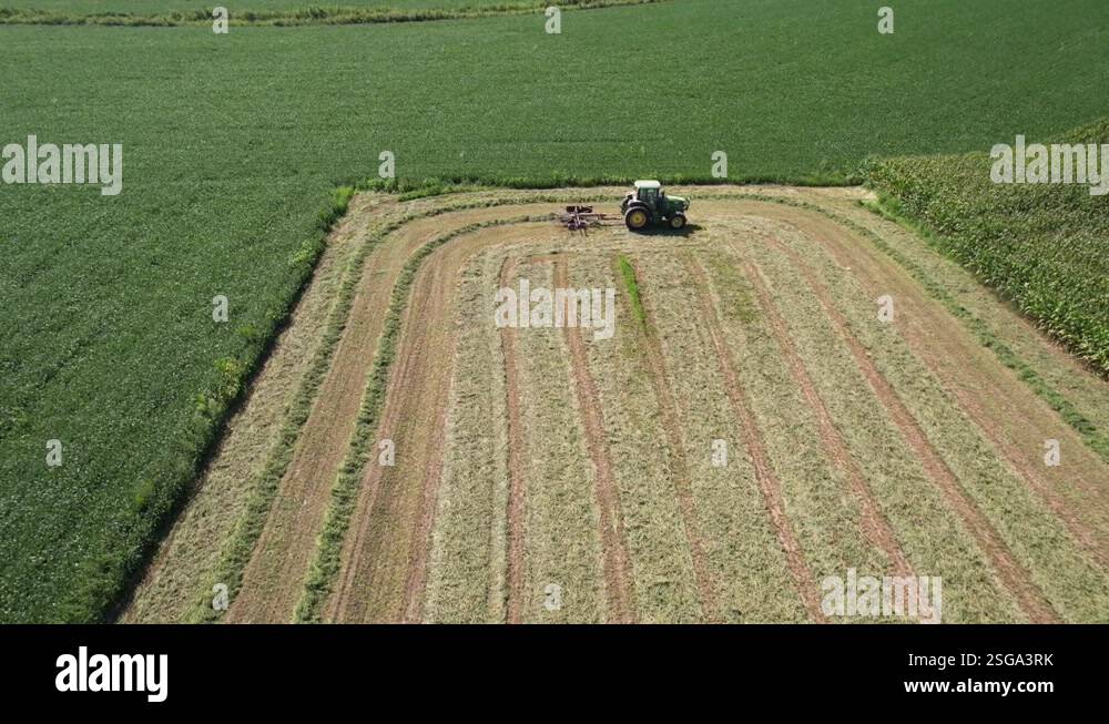 On a farm field in southwest Wisconsin, a farmer rakes hay using a ...