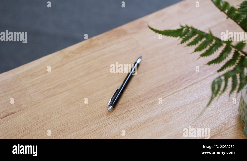 A man picking up a pen from an office table desk while leaving work ...