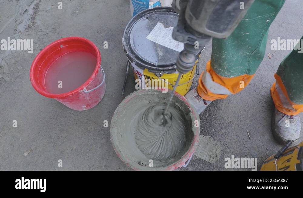 Mixing mortar in a bucket. The mortar is kneaded in a bucket with a ...
