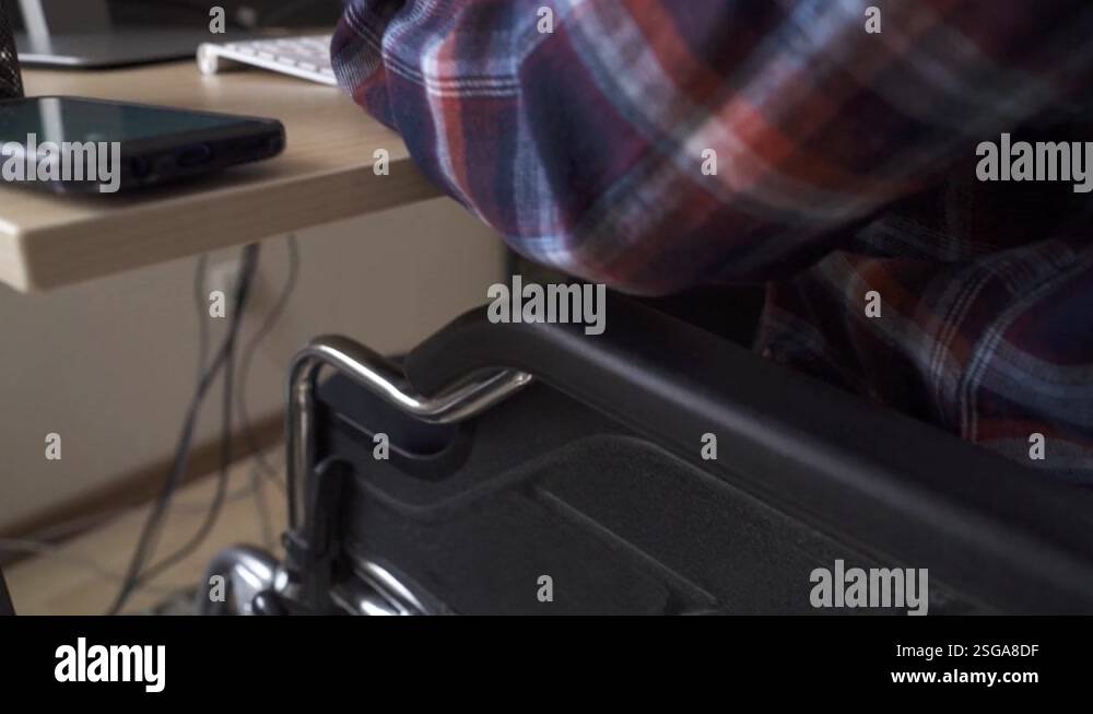 A man with a disability sitting in a wheelchair works at a computer ...