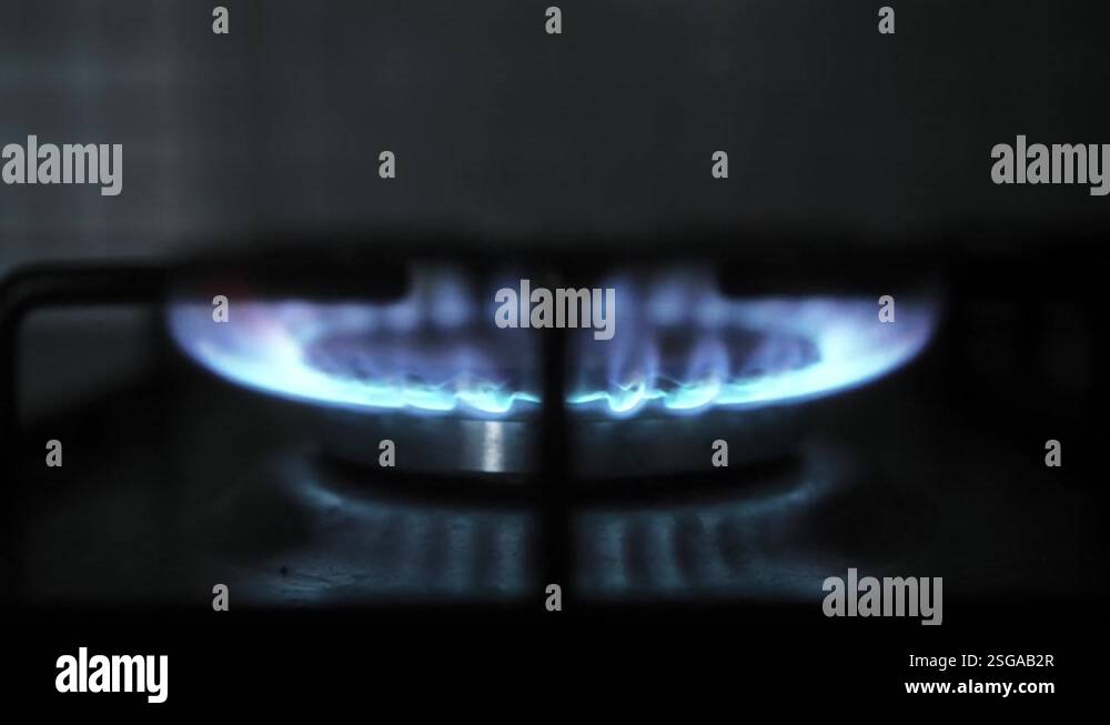 Gas stove being turned on by a lit burner close up. Natural gas concept ...