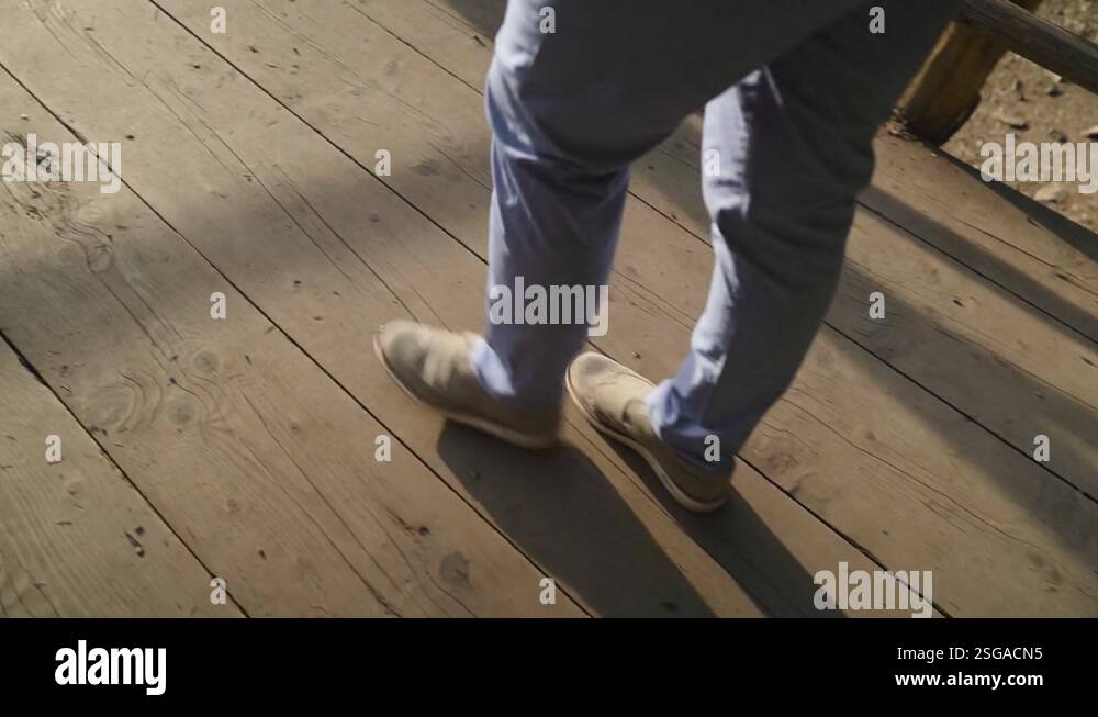 Male person in blue pants and in elegant shoes moving slowly on wooden ...