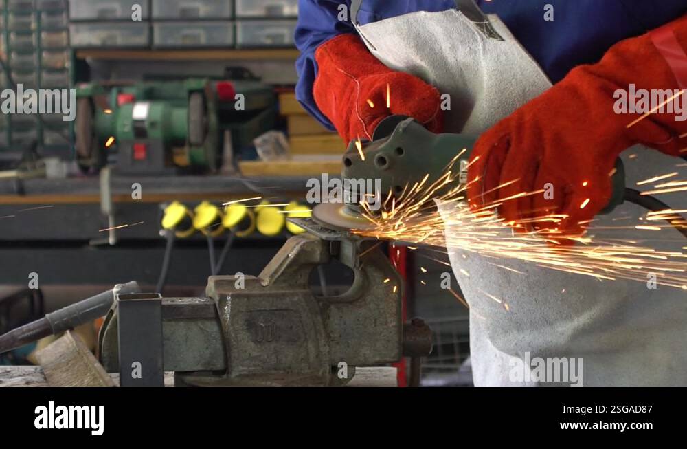 Slowmotion worker in special clothes and gloves grinding metal with ...