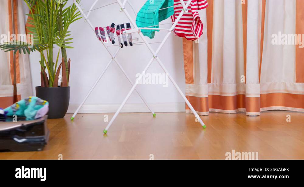 Clothes are on drying rack. Robot vacuum cleaner with socks moves Stock ...