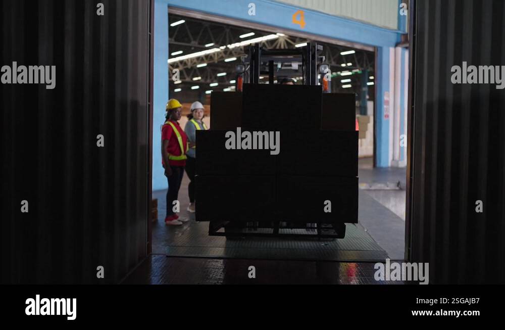 Forklift driver loading a shipping cargo container pallet with ...