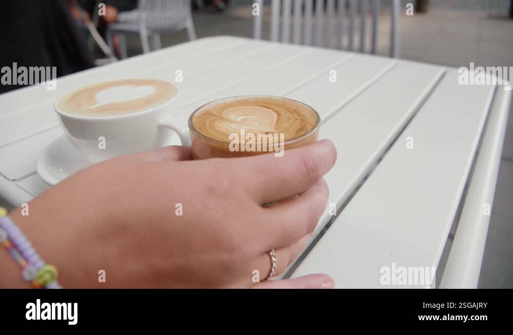 Hand of Woman grabbing flat white from table at café. 4K. Close Up ...