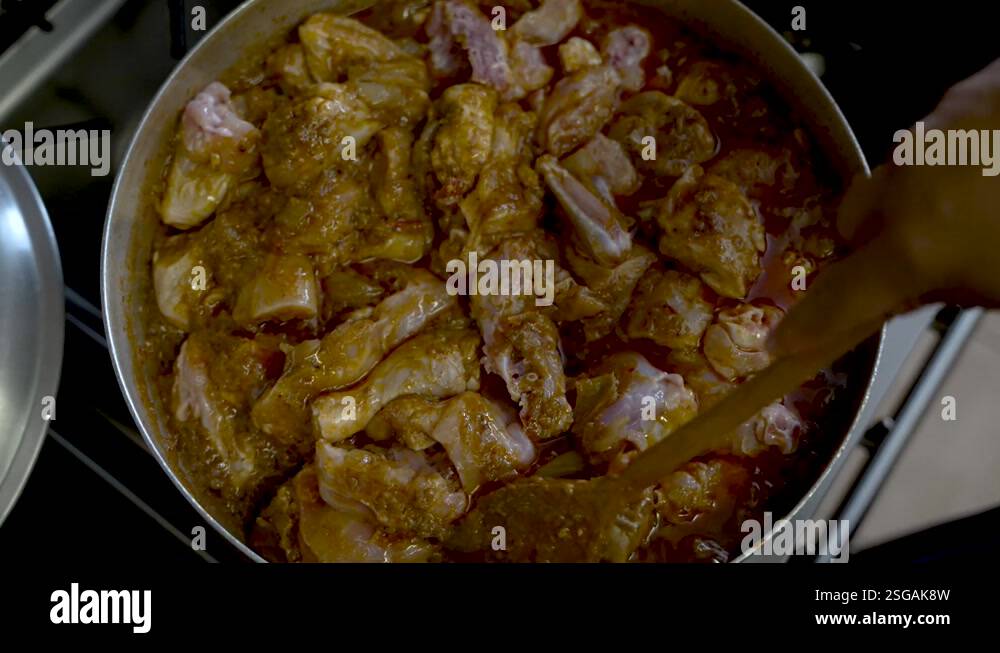 Birds Eye View Of Chicken Pieces Being Stirred In Rich Curry Inside ...