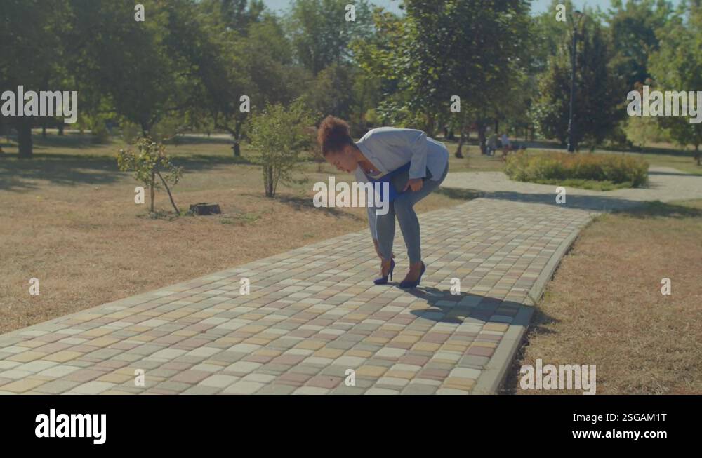 Lovely black female in high heels having ankle sprain during walk ...