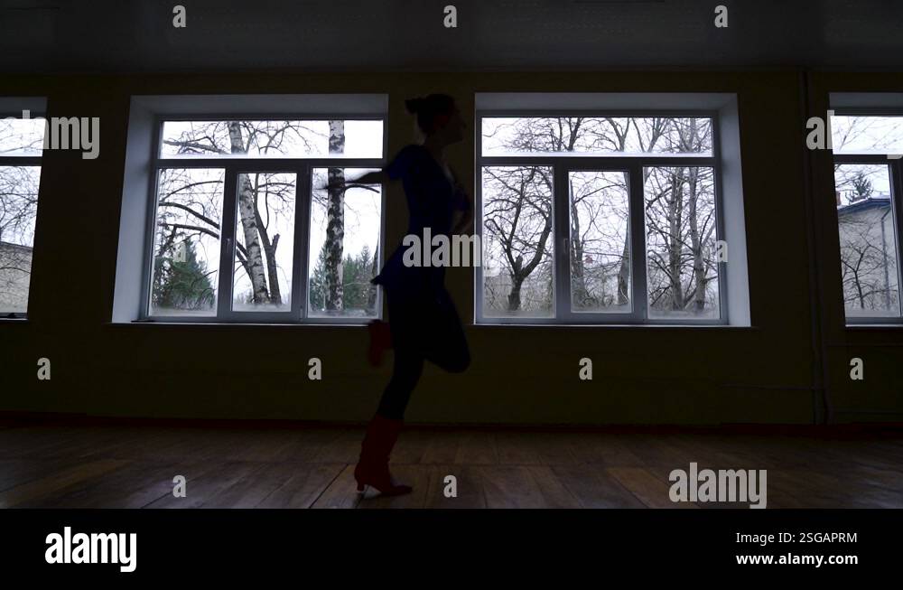 Silhouette of a dancing ballerina training rotation around in the dark ...