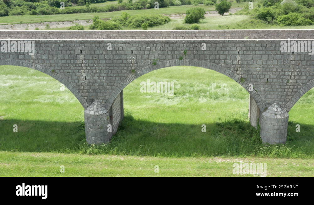 Old arch bridge made of stone over a green grassy field - long vintage ...