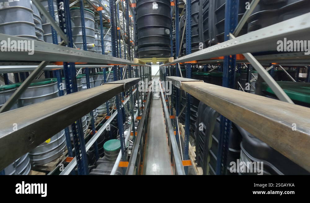inside a narrow industrial rack, a forklift is moving forward slowly to ...