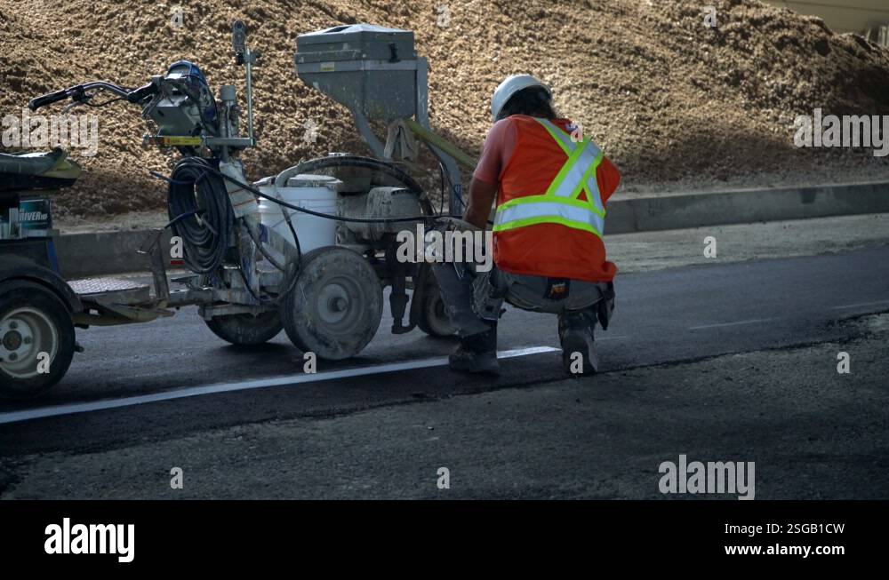 Man painting and resurfacing road tarmac. Manual labour job in Canada ...