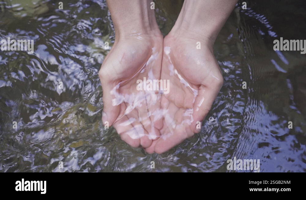One hand lifts the stream water with the palm of the hand. Slow motion ...