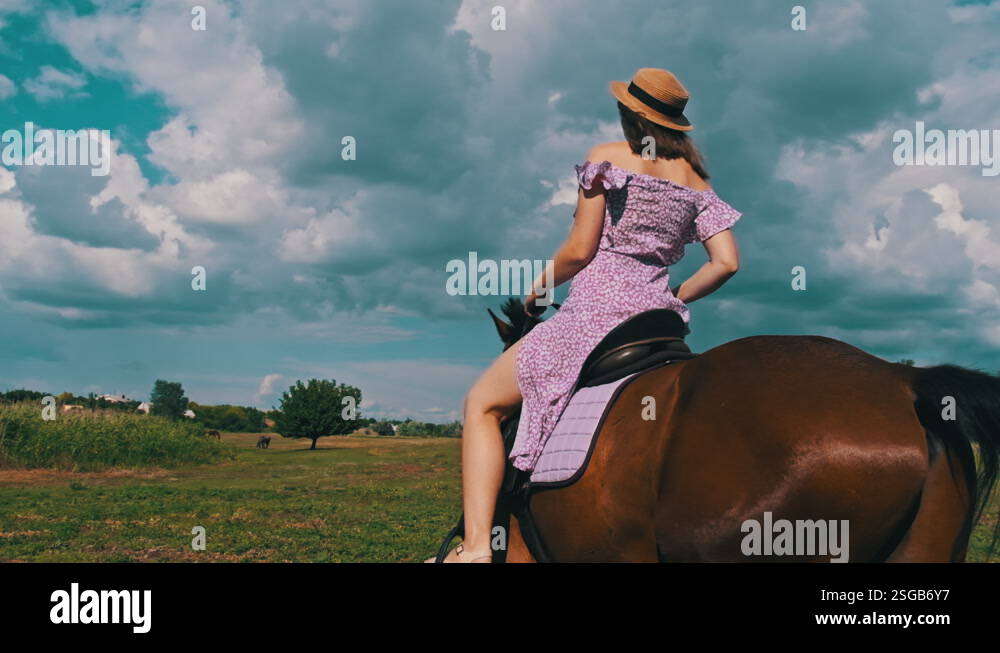 Beautiful Girl in Long Dress and Hat Rides Horse Across Green Field ...