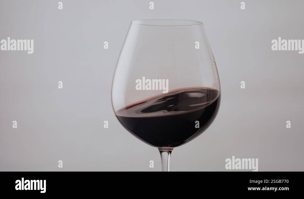 Red wine wave glass goblet on white background close up. Drink swirling ...