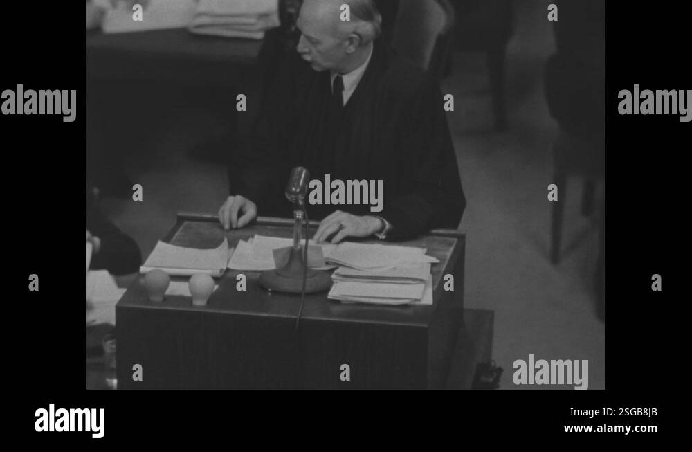 1940s: Man stands at podium, looks at papers. Paper with handwritten ...