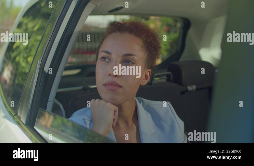 Charming black female looking out car window from backseat during road ...