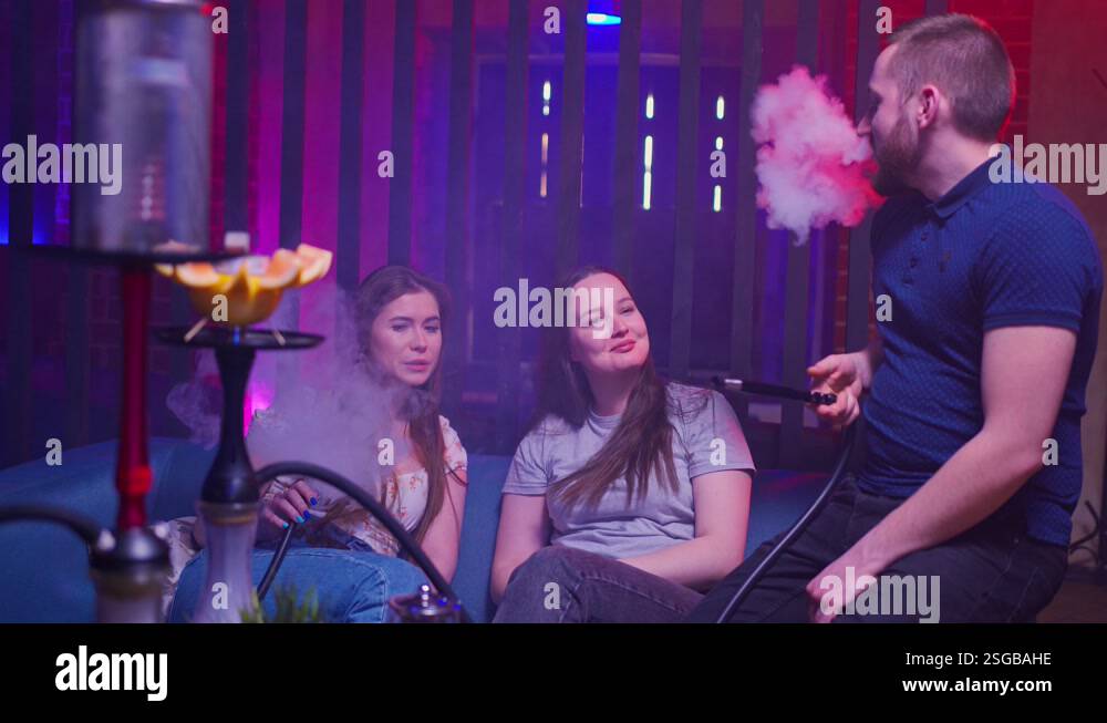 two young women and a young man of European origin are sitting in a ...
