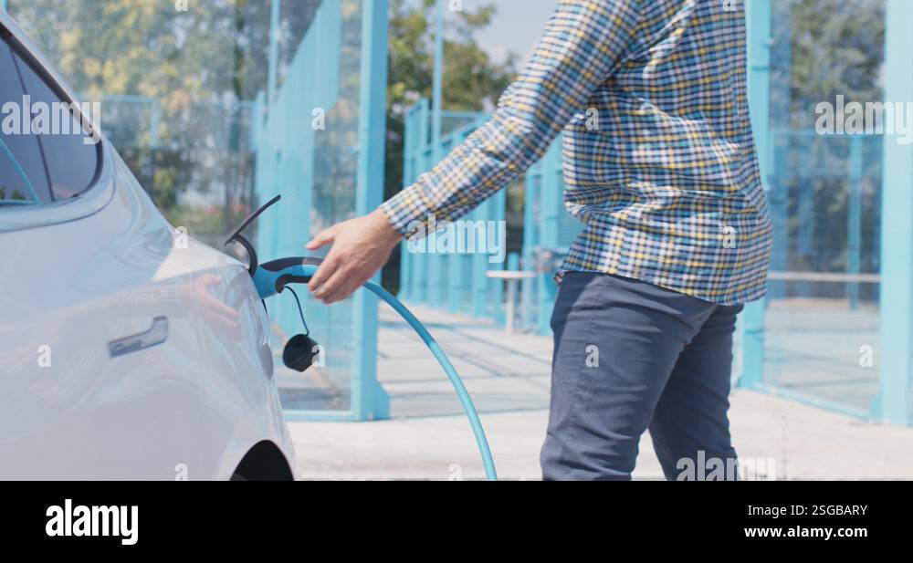 Man in business casual outfit plugging in power cable in charging ...