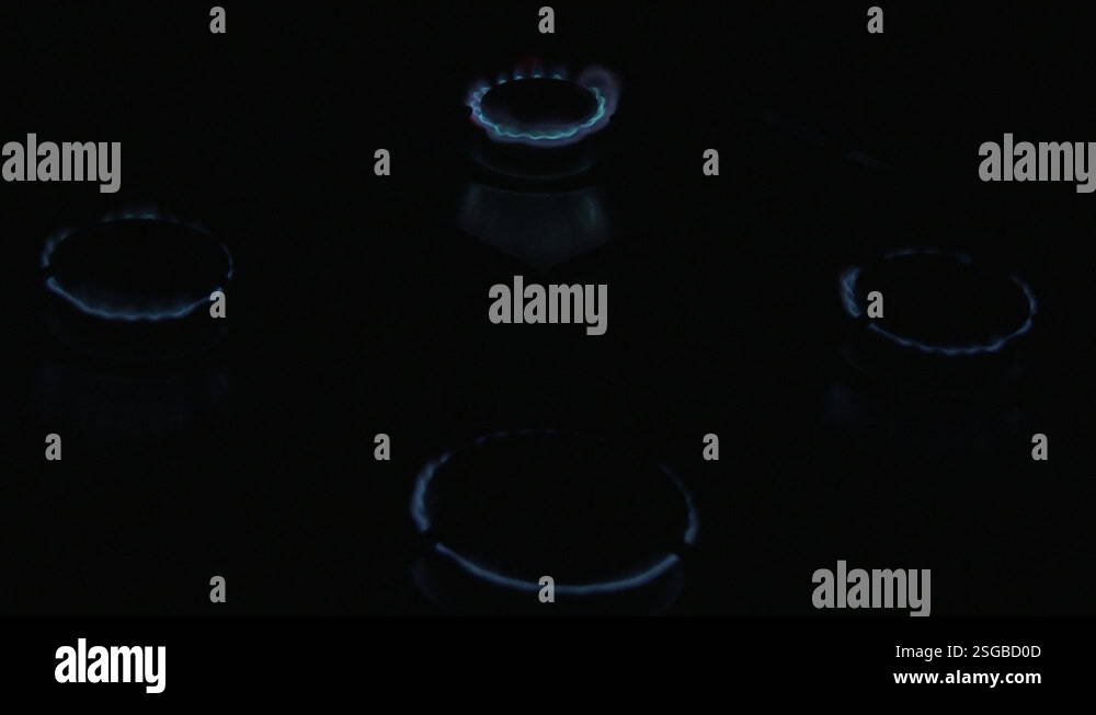 A hand with a gas lighter lights the four burners of a kitchen stove at ...