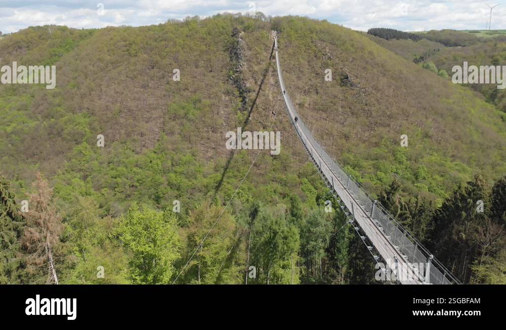 People crossing a valley through Geierlay suspension rope bridge while ...