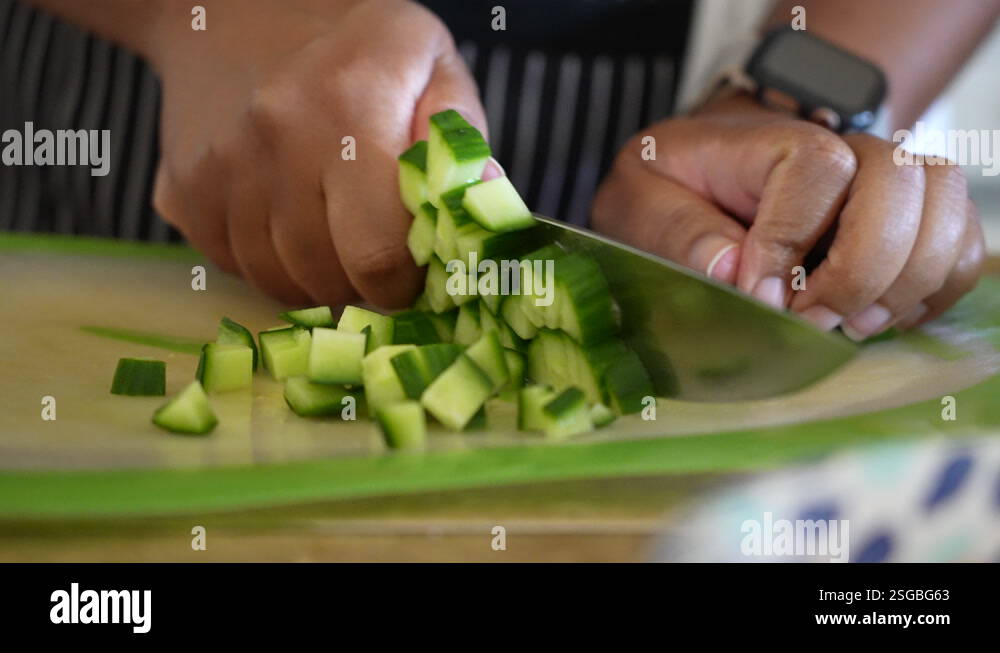 Dicing cucumbers on a cutting board to add to tomato mixture for a ...