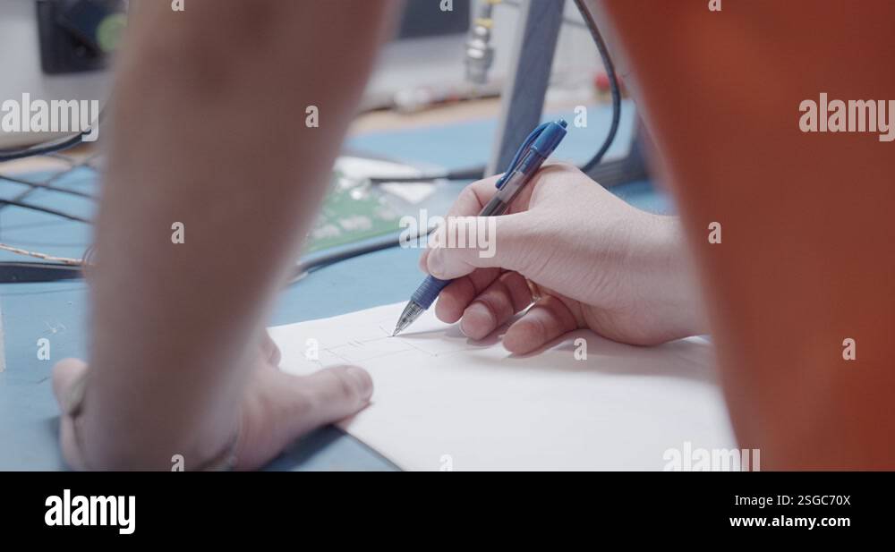 Electronics engineer drawing electronics circuit plan with a blue pen ...