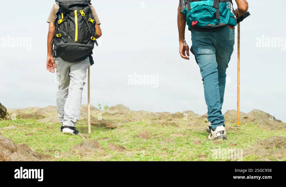 Back view tracking shot of middle aged hikers climbing hill or mountain ...