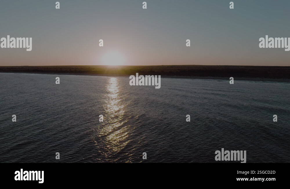Tracking drone shot, flying over the see, with the sun right above the ...
