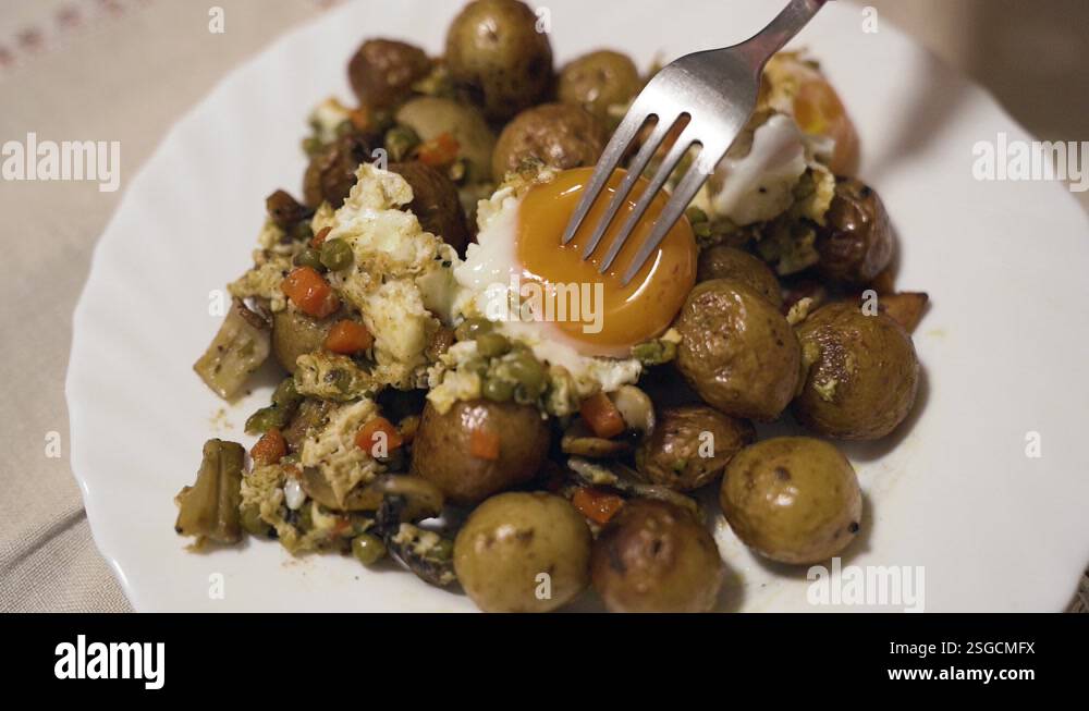 The fork destroys the egg yolk. Potato And fried egg and vegetables ...