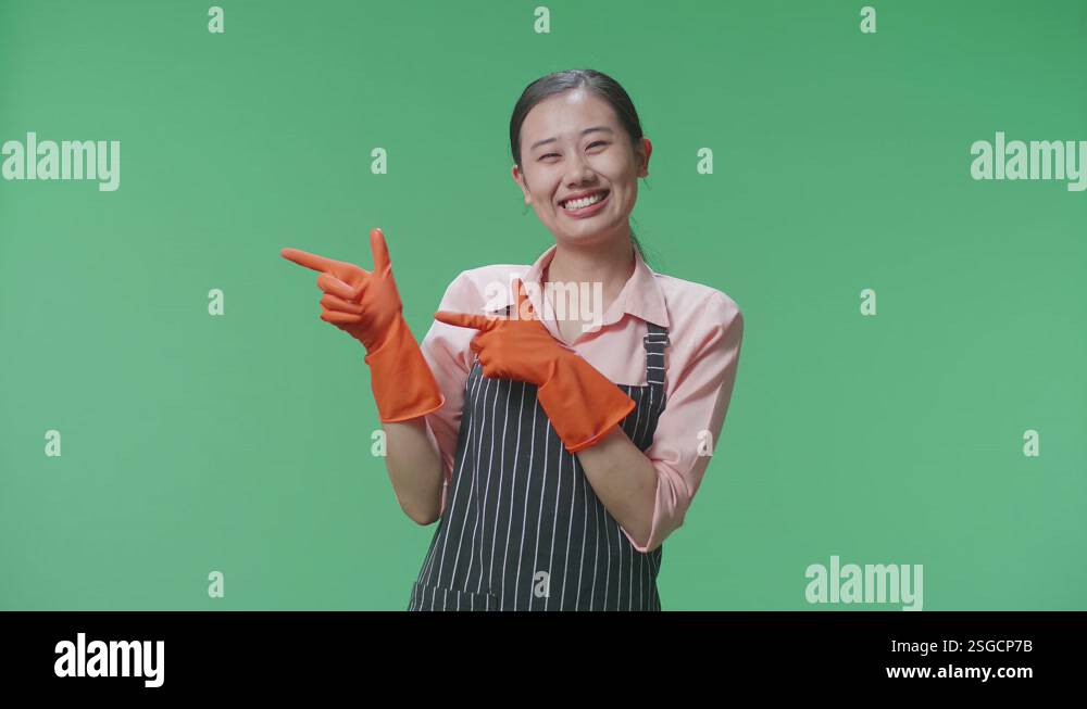 Asian Female Housekeeper With An Apron Smiling And Pointing To The Side ...