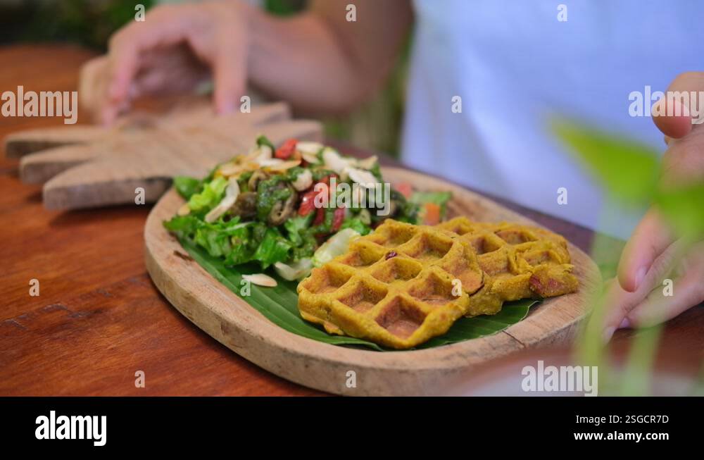 Women's hands put on the table a small plate made of wood in the shape ...