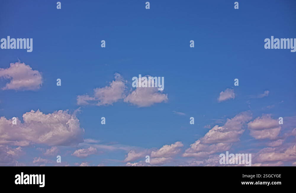 Static time lapse view of a blue sky with white fluffy clouds floating ...