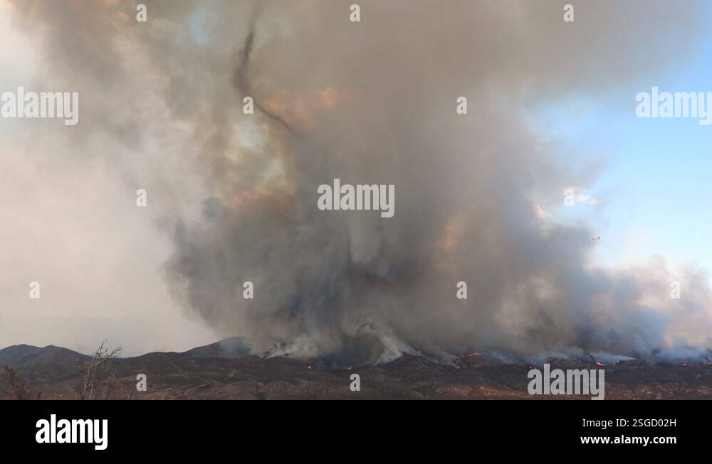 Black and grey smoke coming up from a wildfire burning on a mountain ...