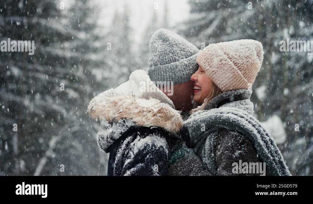 CLose-up of young couple hugging and kissing in winter under falling ...