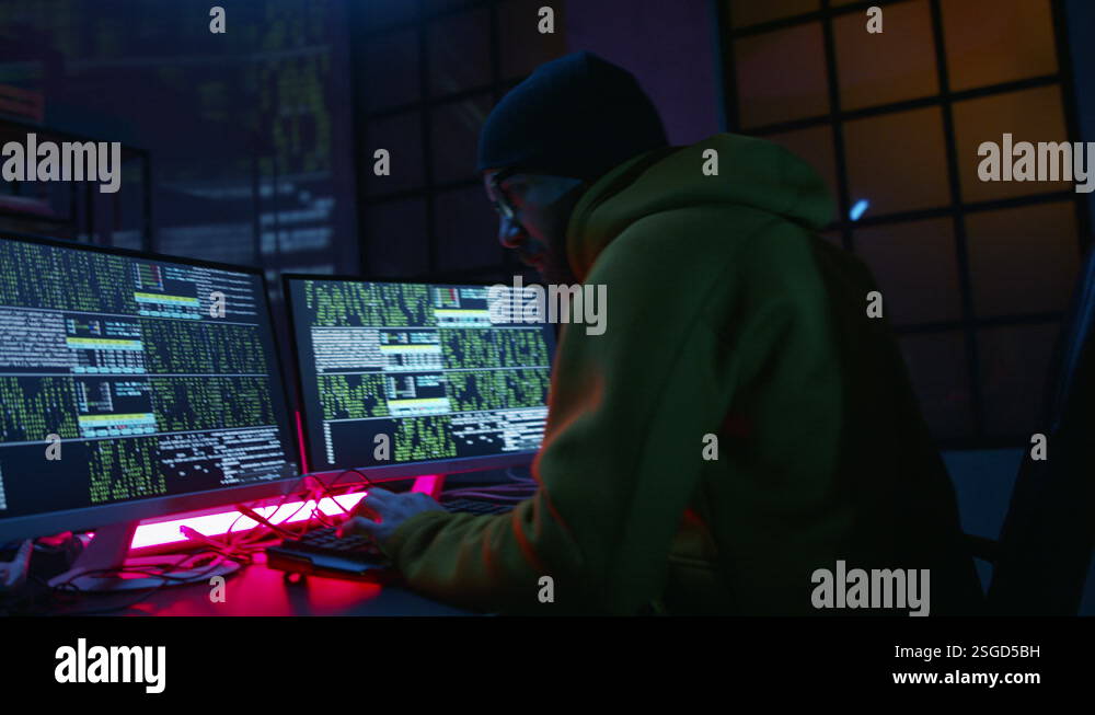 Young man hacker by computer in the dark room at night, cyberwar ...