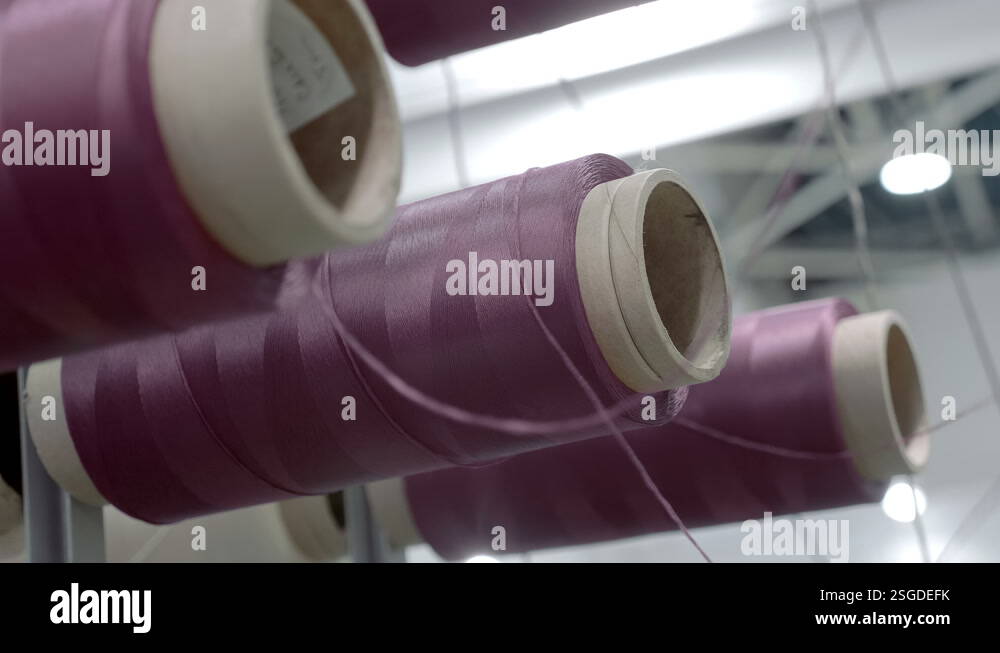 Huge spools of thread of different colors in the industrial equipment ...