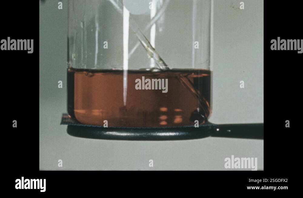 1950s:Clear liquid in a glass beaker stirred, turns brown and boils ...
