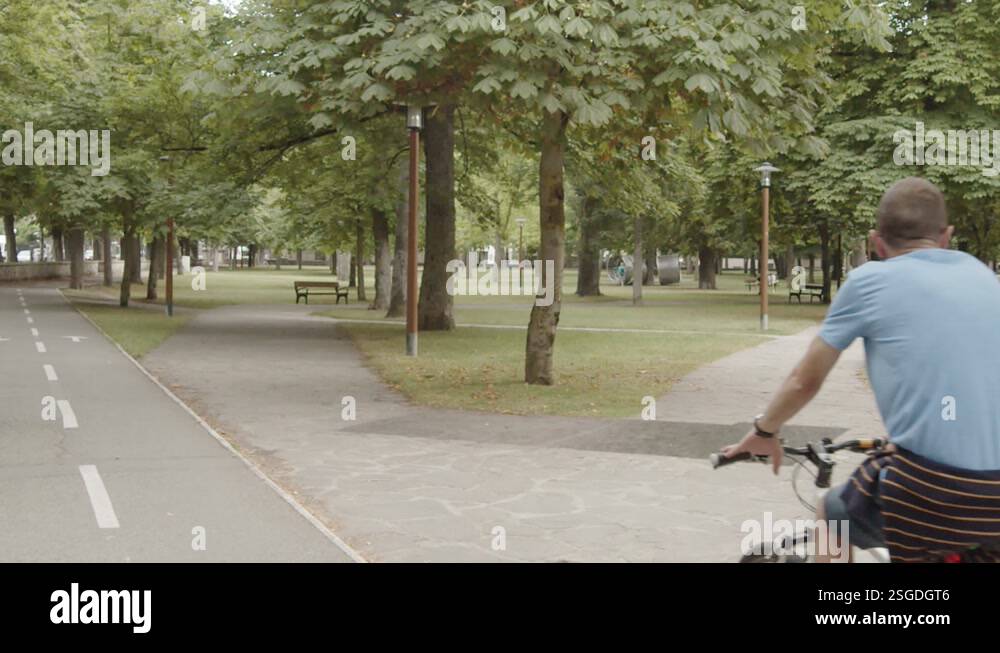Tilt shot of a cycle lane in a park while father and son cross cyling ...