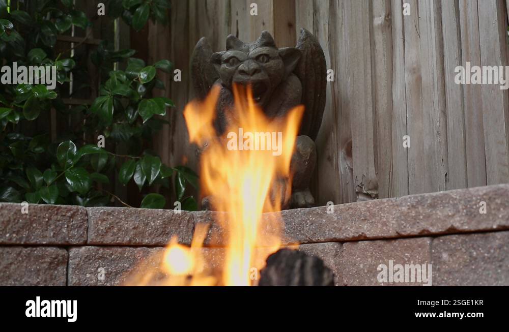 Scary Gargoyle behind the flames of a Carmel Garden fire pit Stock ...