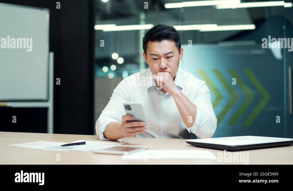 worried asian office worker employee reading bad news using smartphone ...