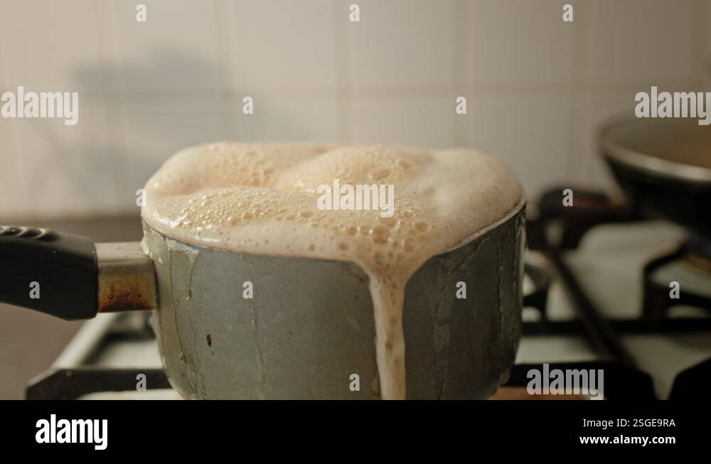Foam pouring over saucepan edge. Thick foam of boiling liquid pouring ...